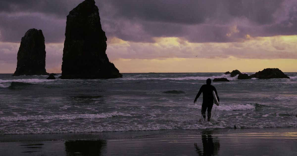Cannon Beach’s iconic rocks share the scene with a surfer and the surf ...